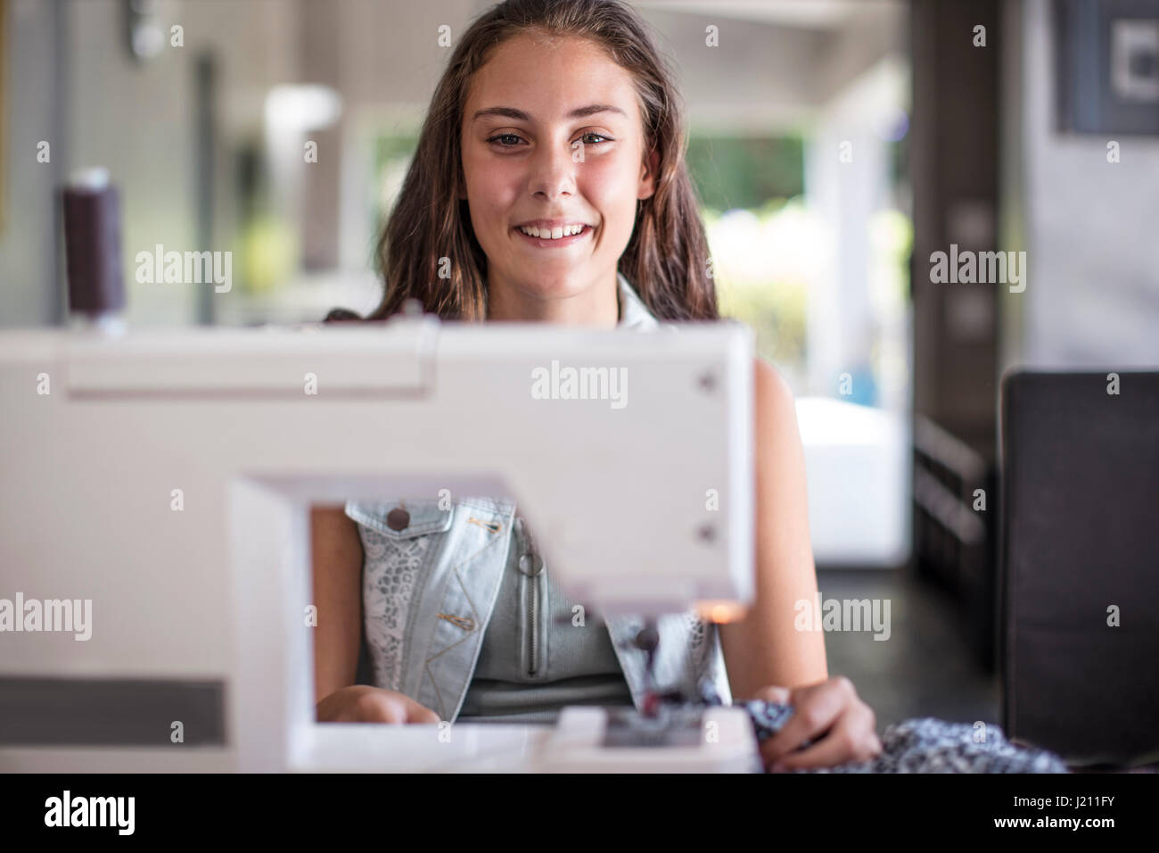 Portrait of smiling girl at sewing machine Stock Photo - Alamy