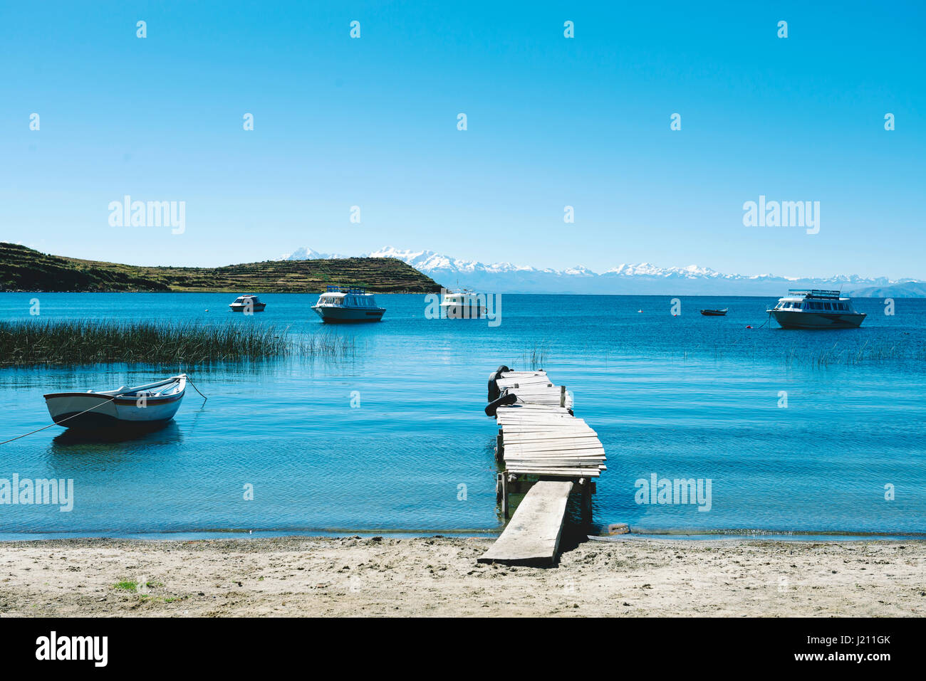 Isla del sol, Titicaca lake, Bolivia. Pier and boats with the Andes in ...