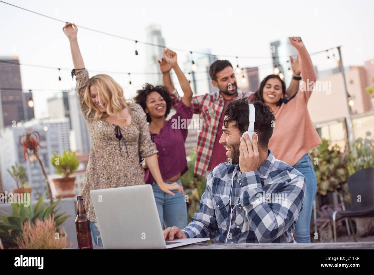 People dancing at rooftop party, with DJ using laptop Stock Photo - Alamy