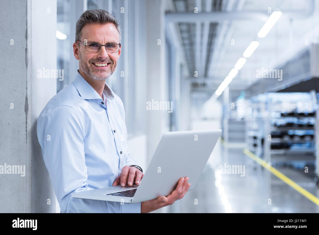 Manager on shop floor of factory using laptop Stock Photo - Alamy