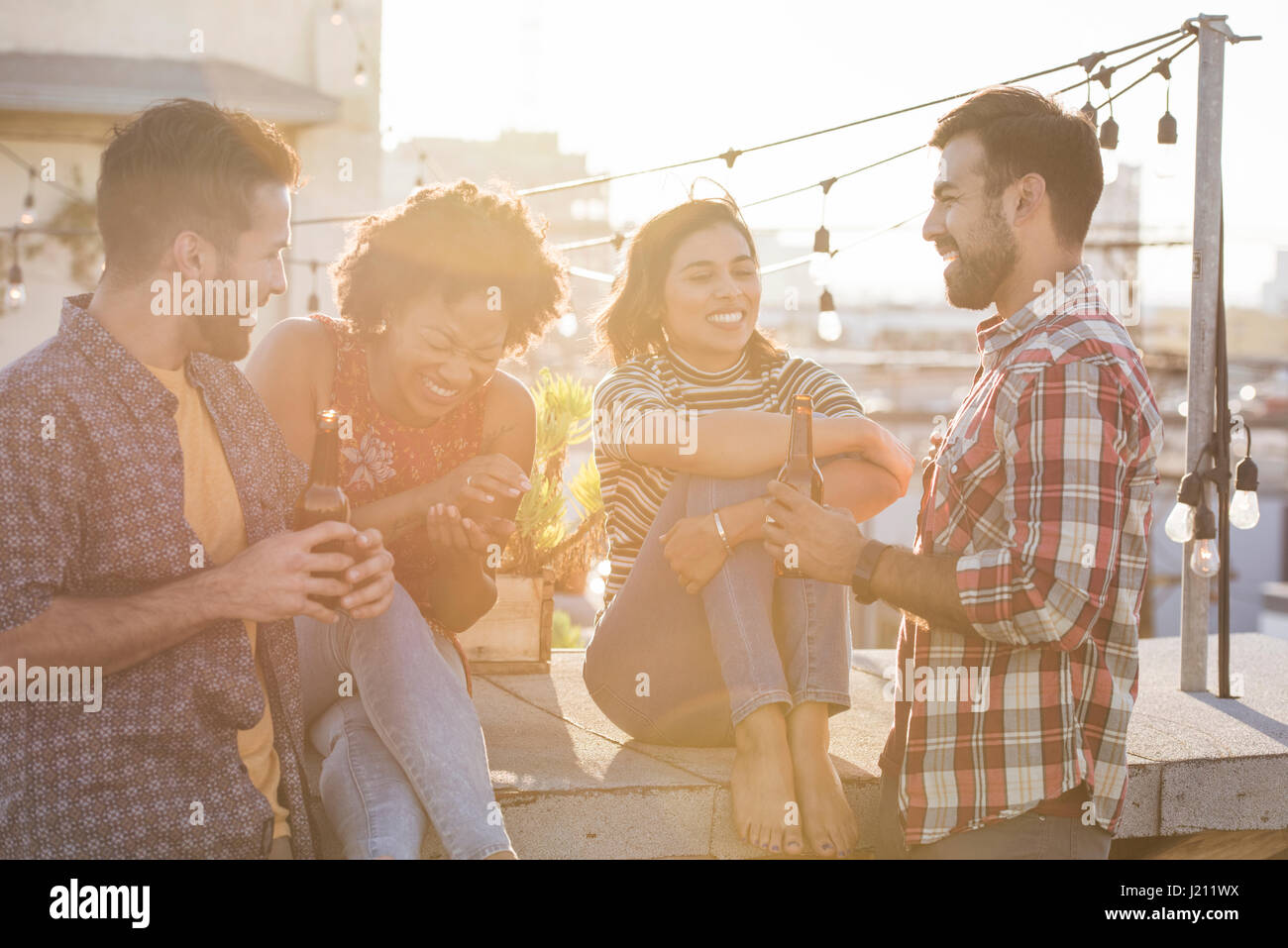 Friends having a rooftop party, chatting and drinking beer Stock Photo ...