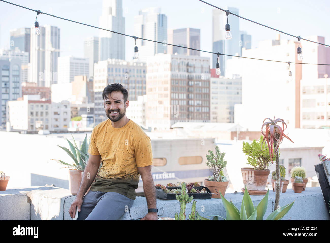 Young man sitting on rooftop terrace Stock Photo - Alamy