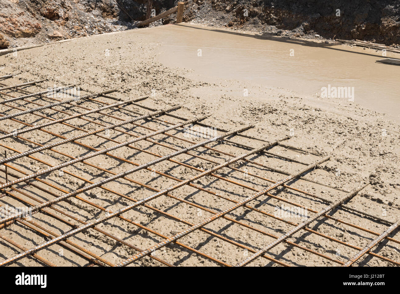 The wet concrete is poured on a steel reinforcement to form strong ...