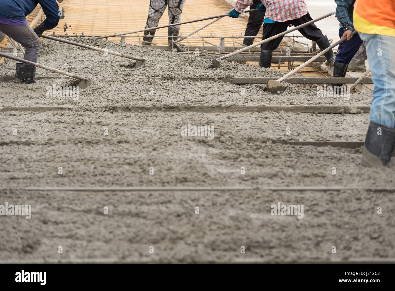Construction workers are using the newly poured cement spreaders into ...