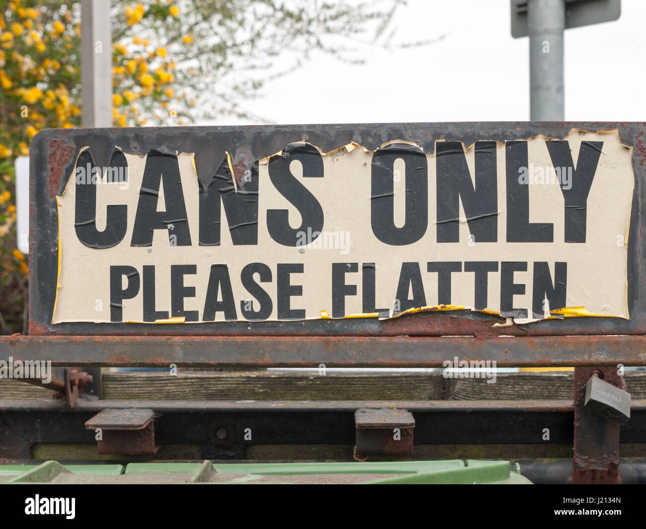 a tattered outside sign at recycling plant and bins saying cans only ...