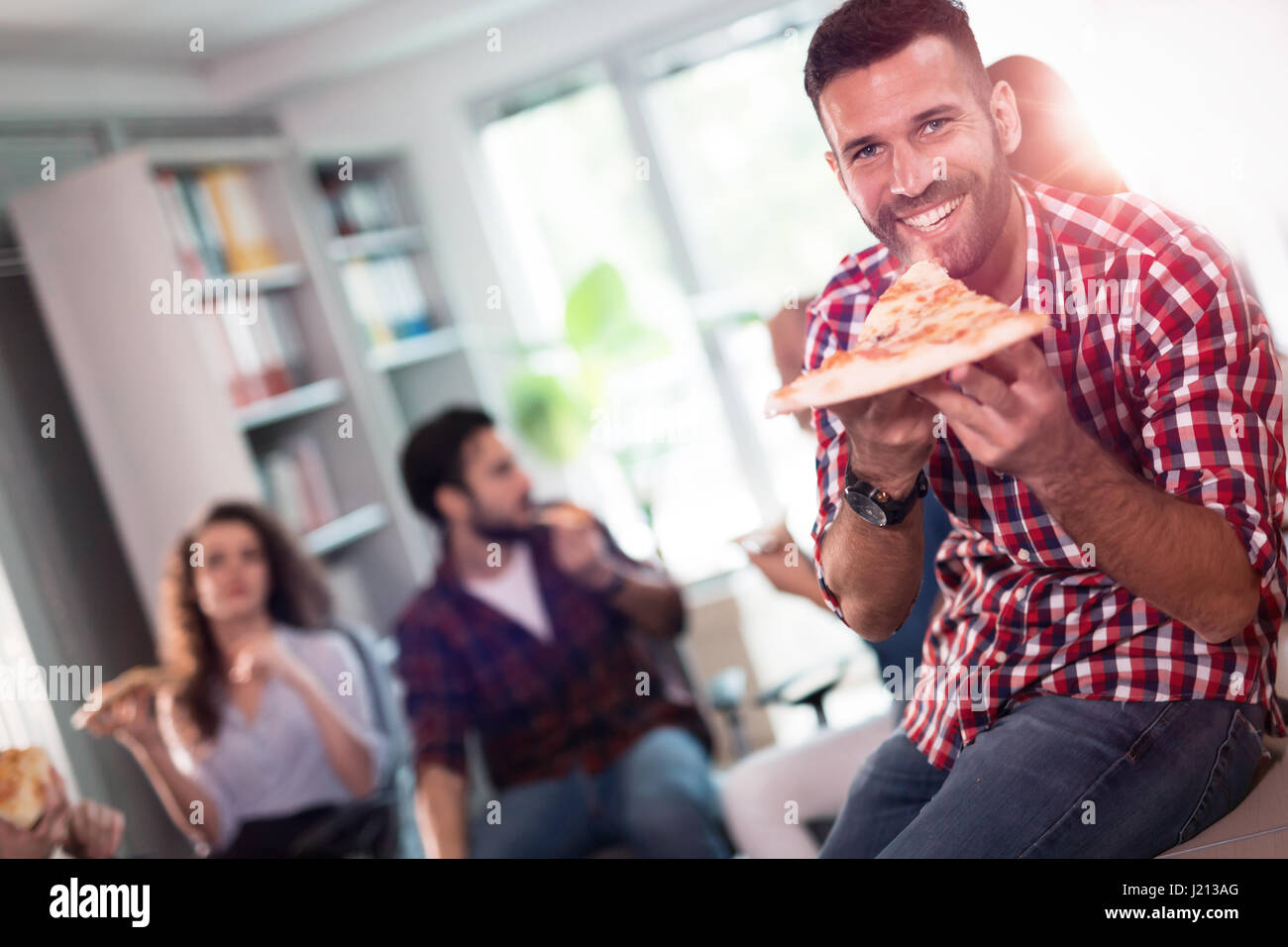 Coworkers eating pizza during work break at office Stock Photo - Alamy