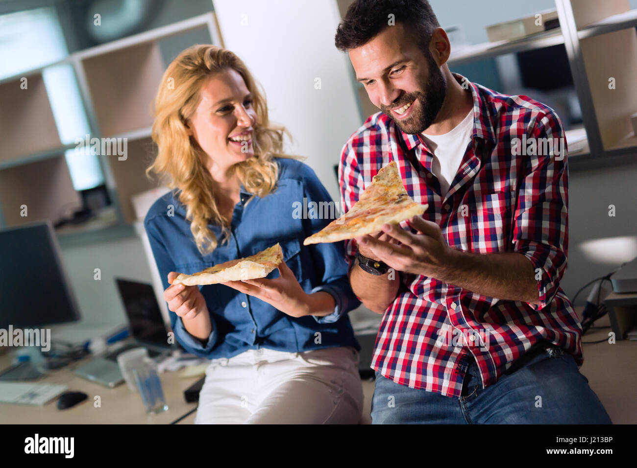 Coworkers eating pizza during work break at office Stock Photo - Alamy