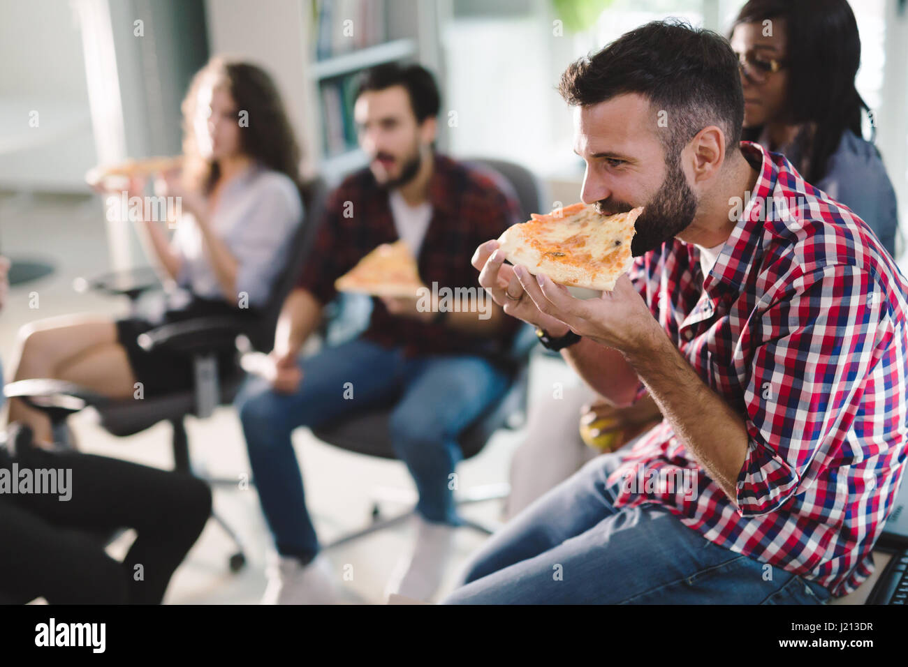 Coworkers eating pizza during work break at office Stock Photo - Alamy