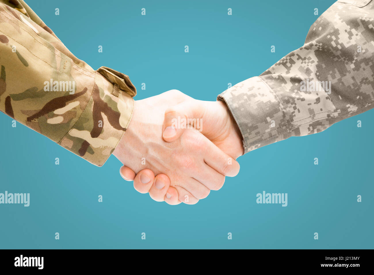 Close up shot of two military men shaking hands on light blue ...