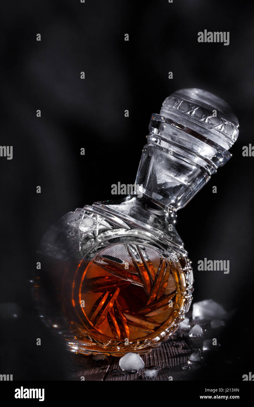 Crystal decanter full of strong alcoholic drink on a wooden table, dark ...