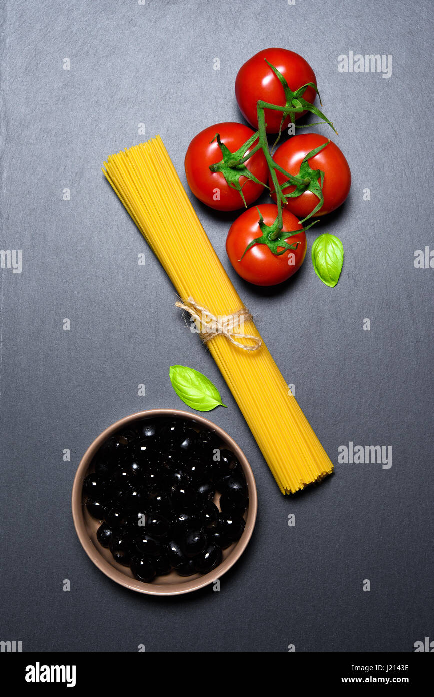 Top view: pasta or italian spaghetti, tomatoes, olives and oregano on ...