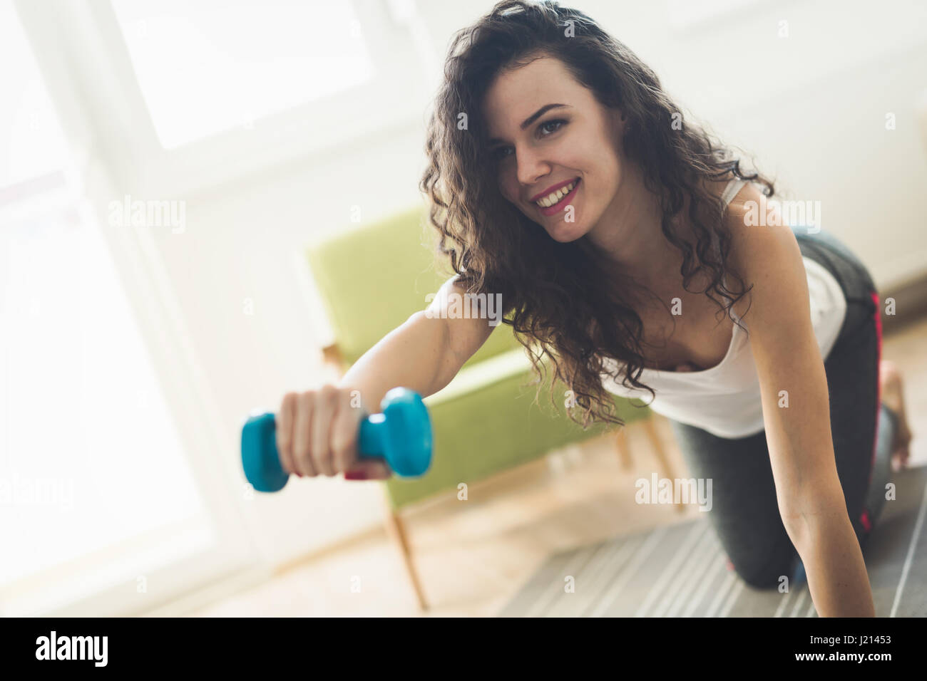 Happy determined woman working out with dumbbells at home Stock Photo ...