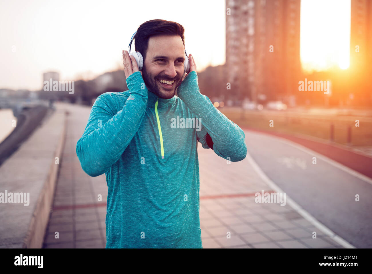 Handsome jogger listening to music while exercising Stock Photo - Alamy