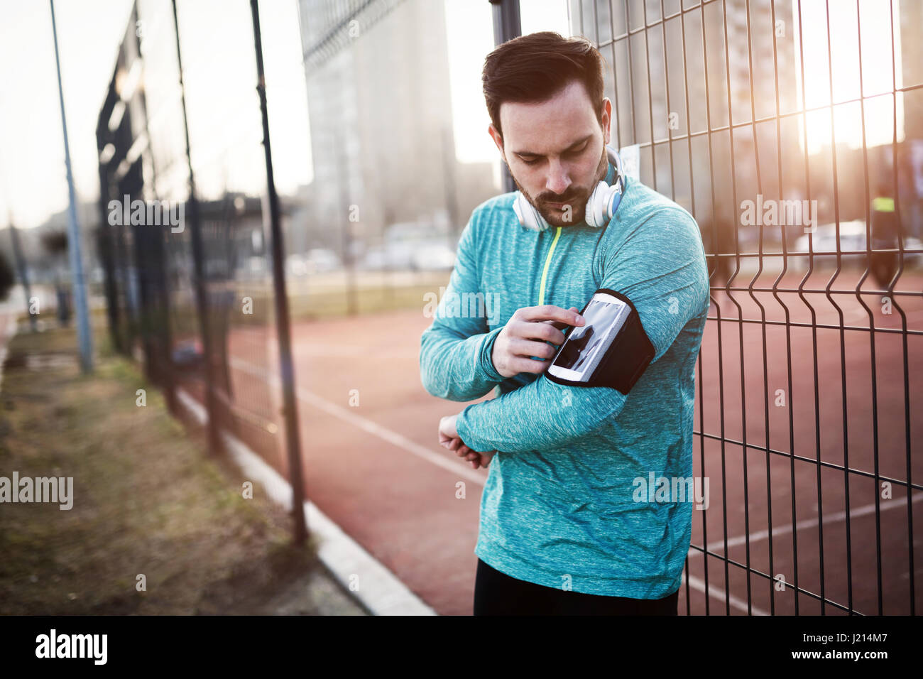 Handsome jogger listening to music while exercising Stock Photo - Alamy