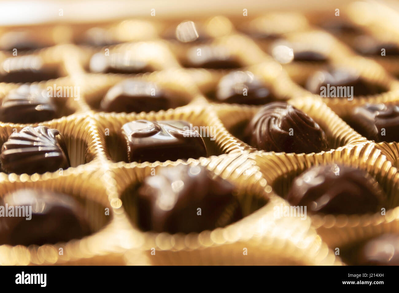 Chocolate candies of different shapes in a gold box, a perspective view ...