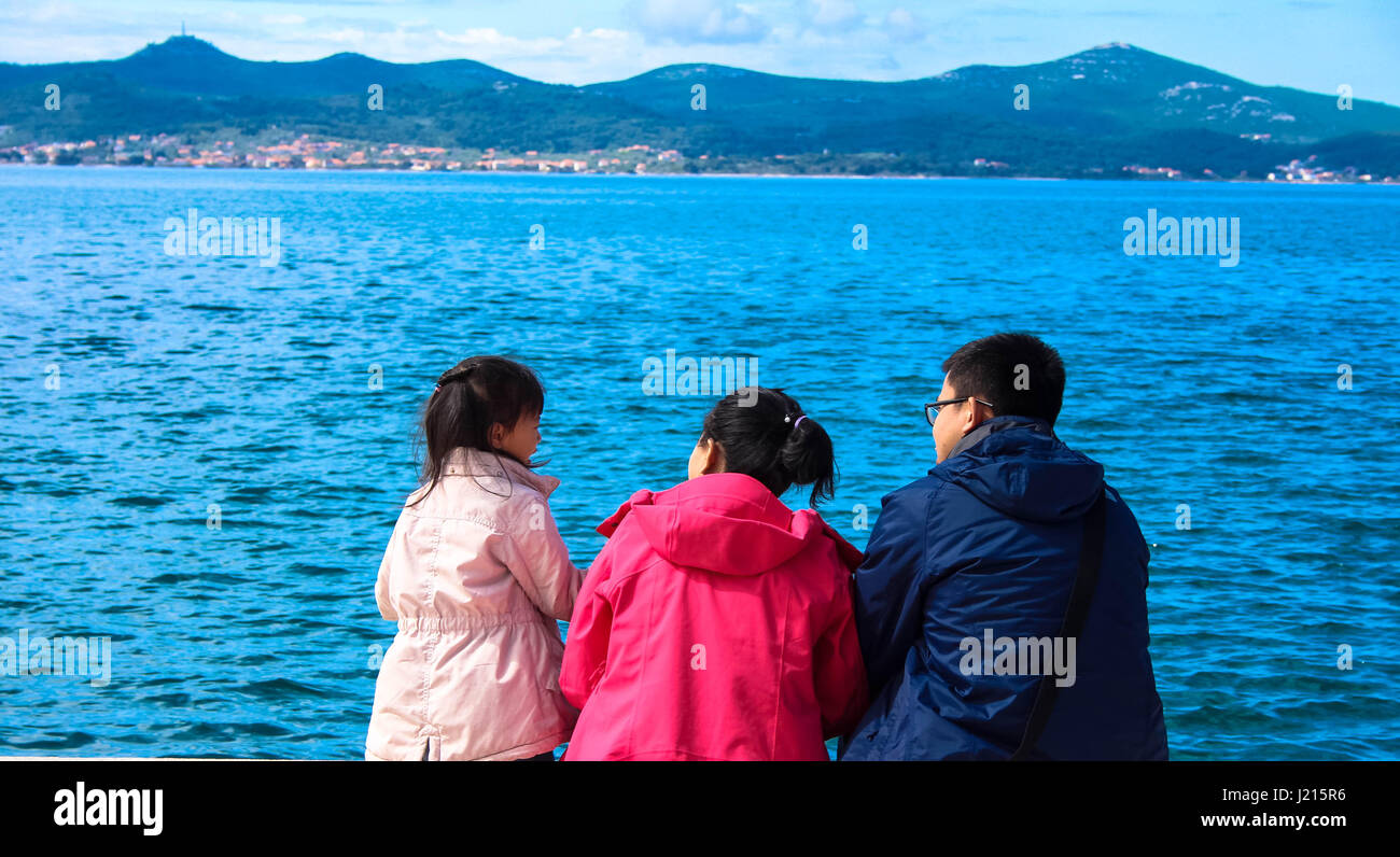 Young family looking out to sea Stock Photo - Alamy