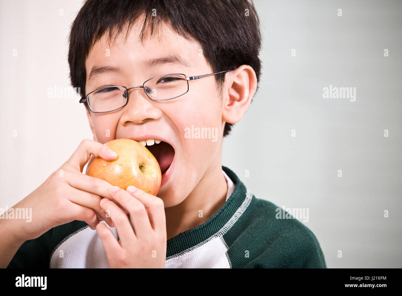 A shot of an asian boy eating an apple Stock Photo - Alamy