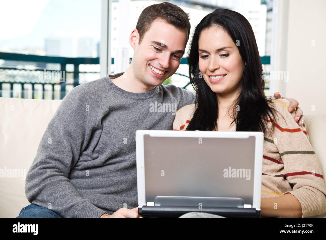 A happy couple sitting on the couch at home browsing internet Stock ...