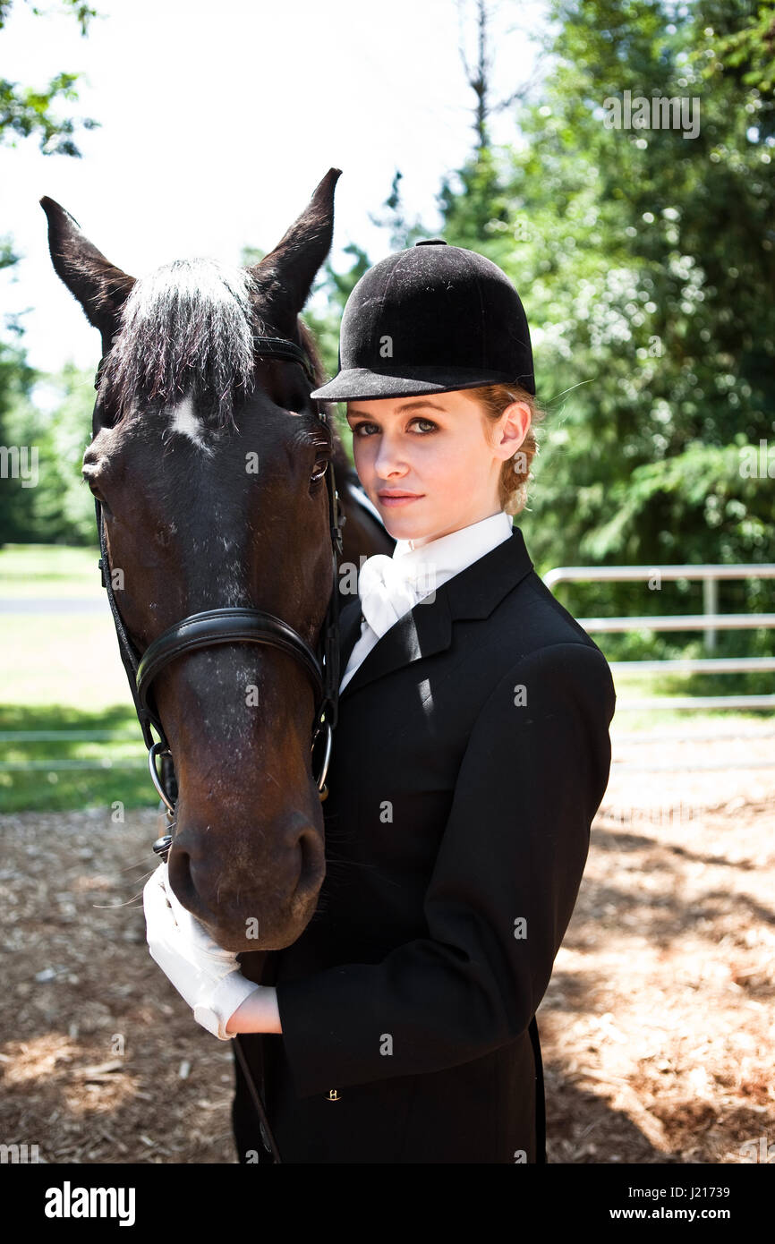 A caucasian girl getting ready for a horseback riding posing with her ...
