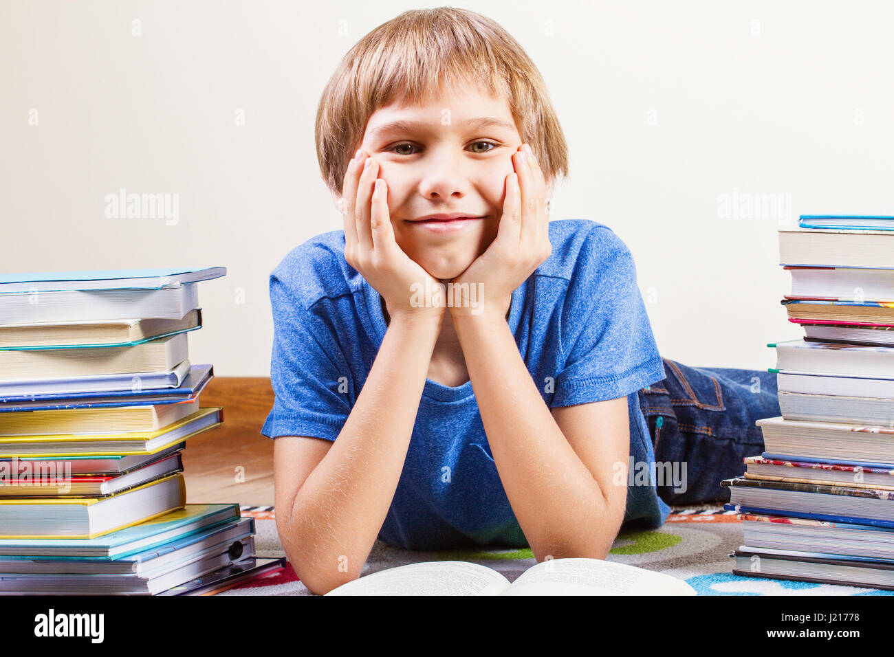 Smiling boy between the stacks of books Stock Photo - Alamy