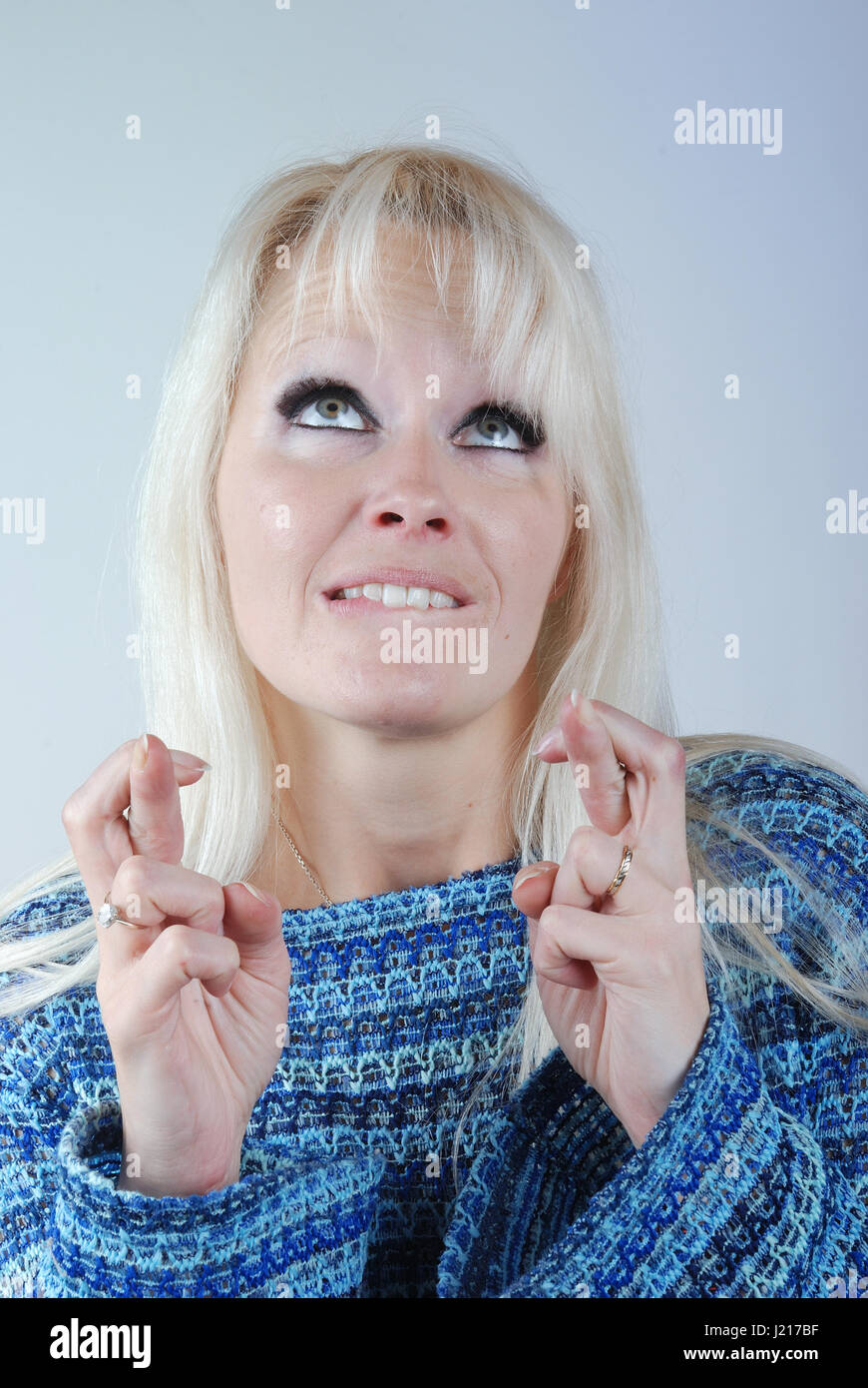 Young blond woman fingers crossed Stock Photo - Alamy