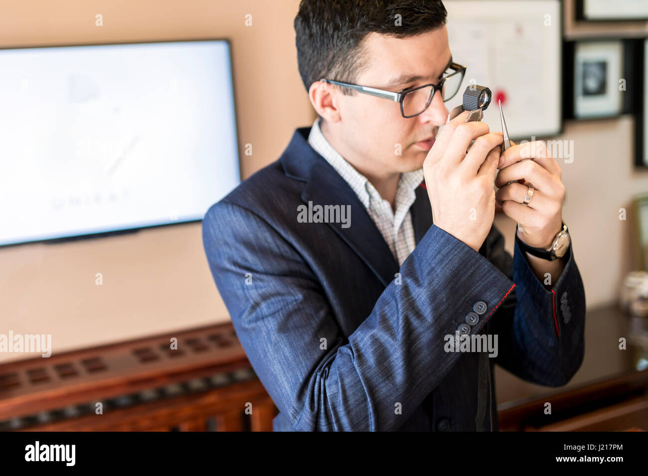 Jeweler looking at diamond through loupe to inspect it Stock Photo - Alamy