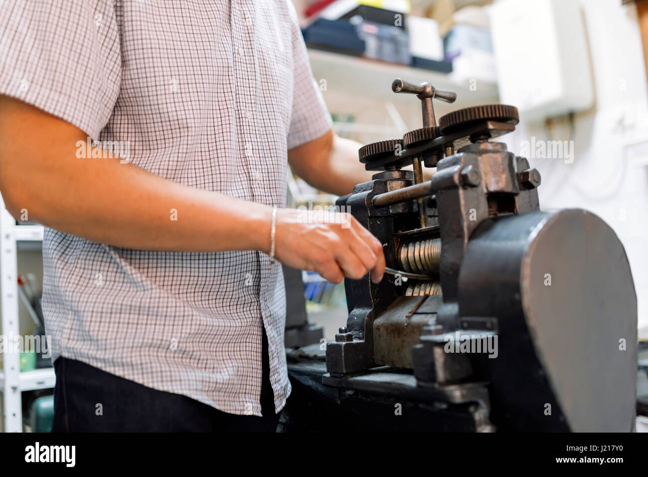 Goldsmith using machine to make metal thinner Stock Photo - Alamy