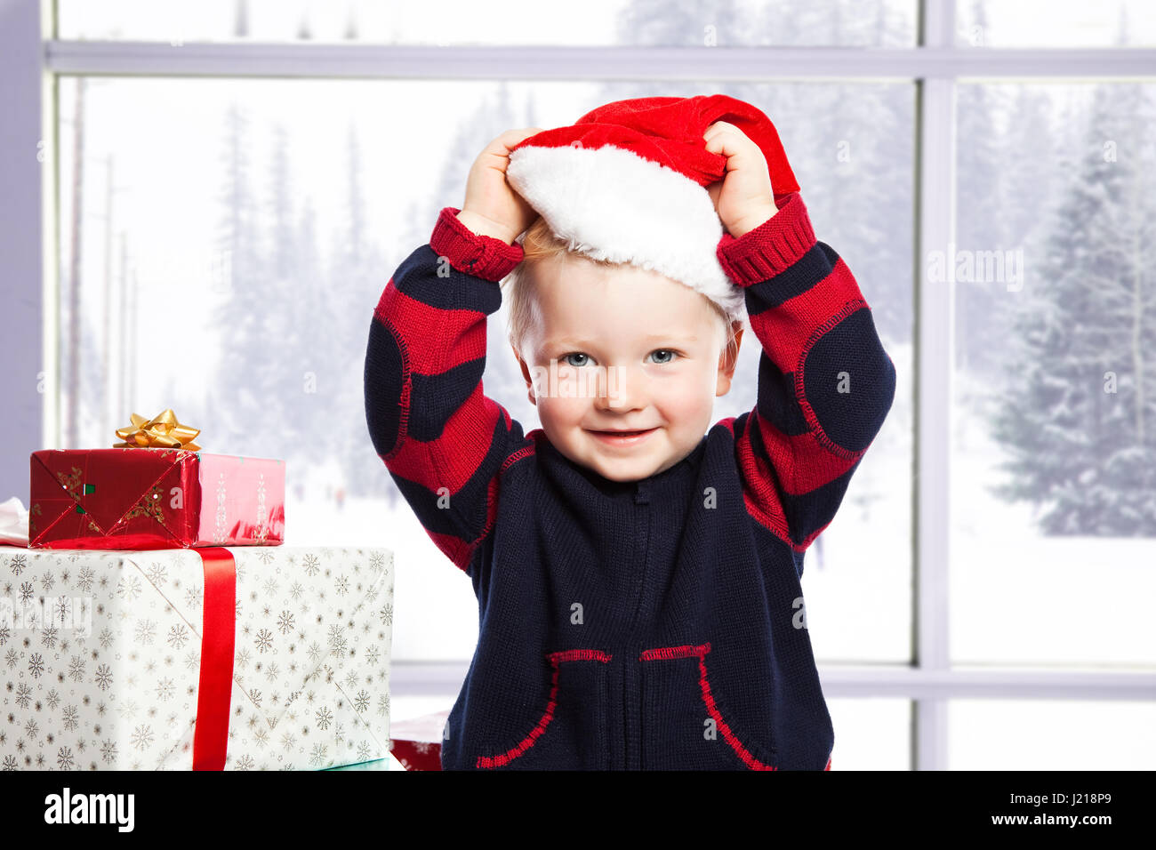 A caucasian boy wearing a santa hat with a lot of christmas gift Stock ...