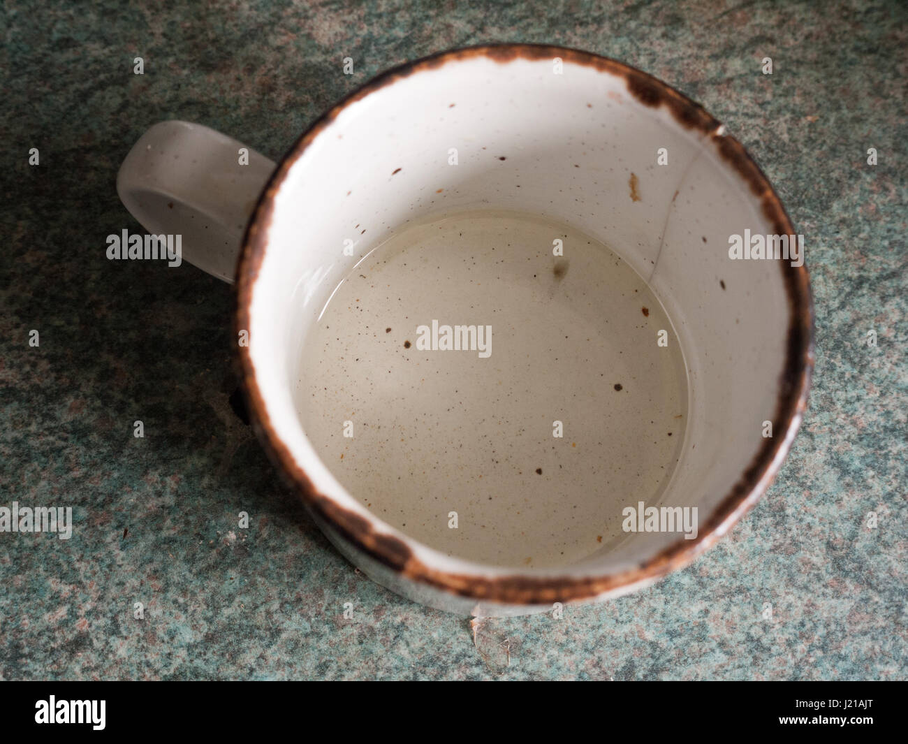 A Small White and Black Spotted Cup with A Rusty Rim and with A Small ...
