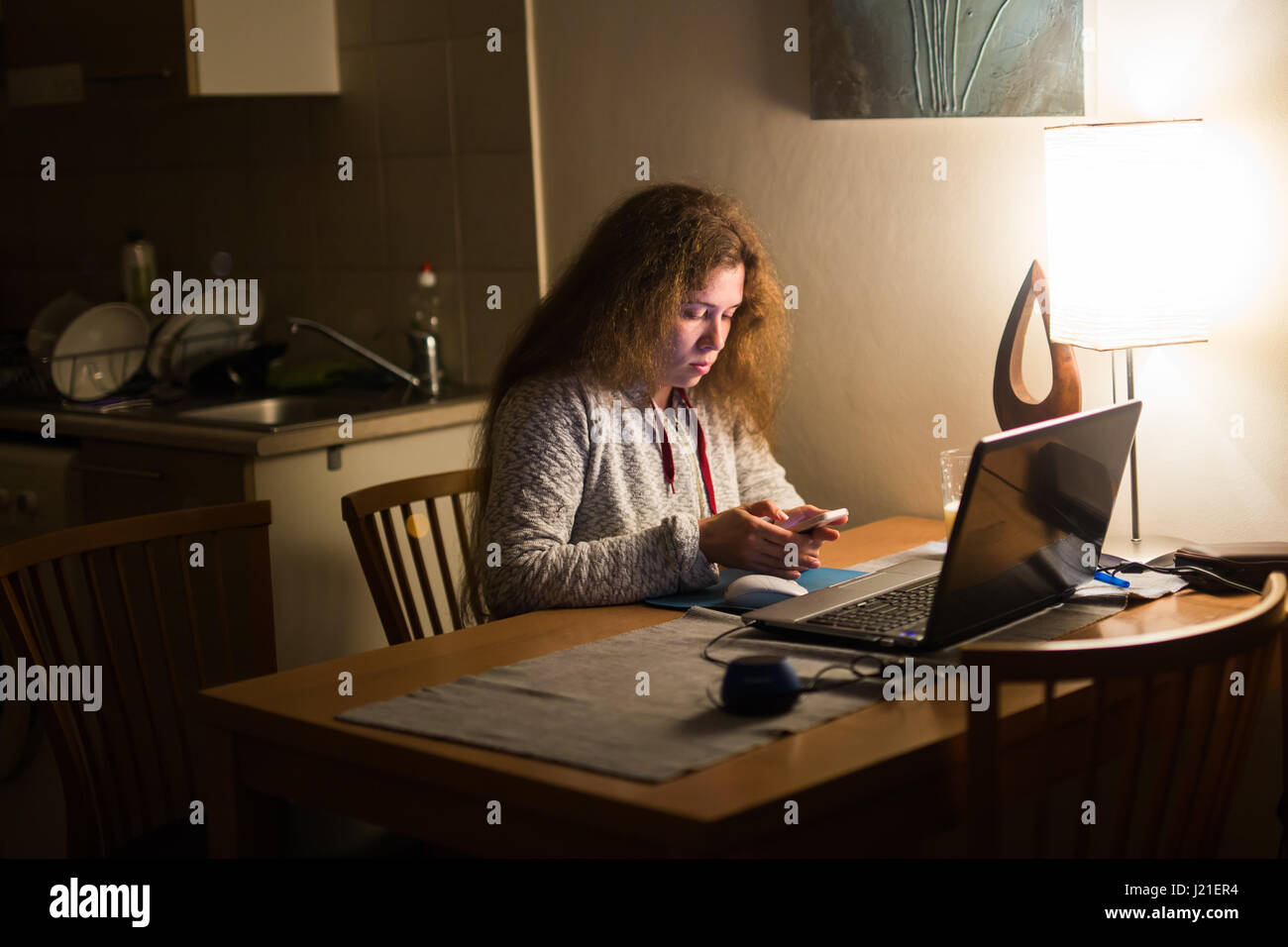 young woman late at night texting using mobile phone sleepy and tired ...