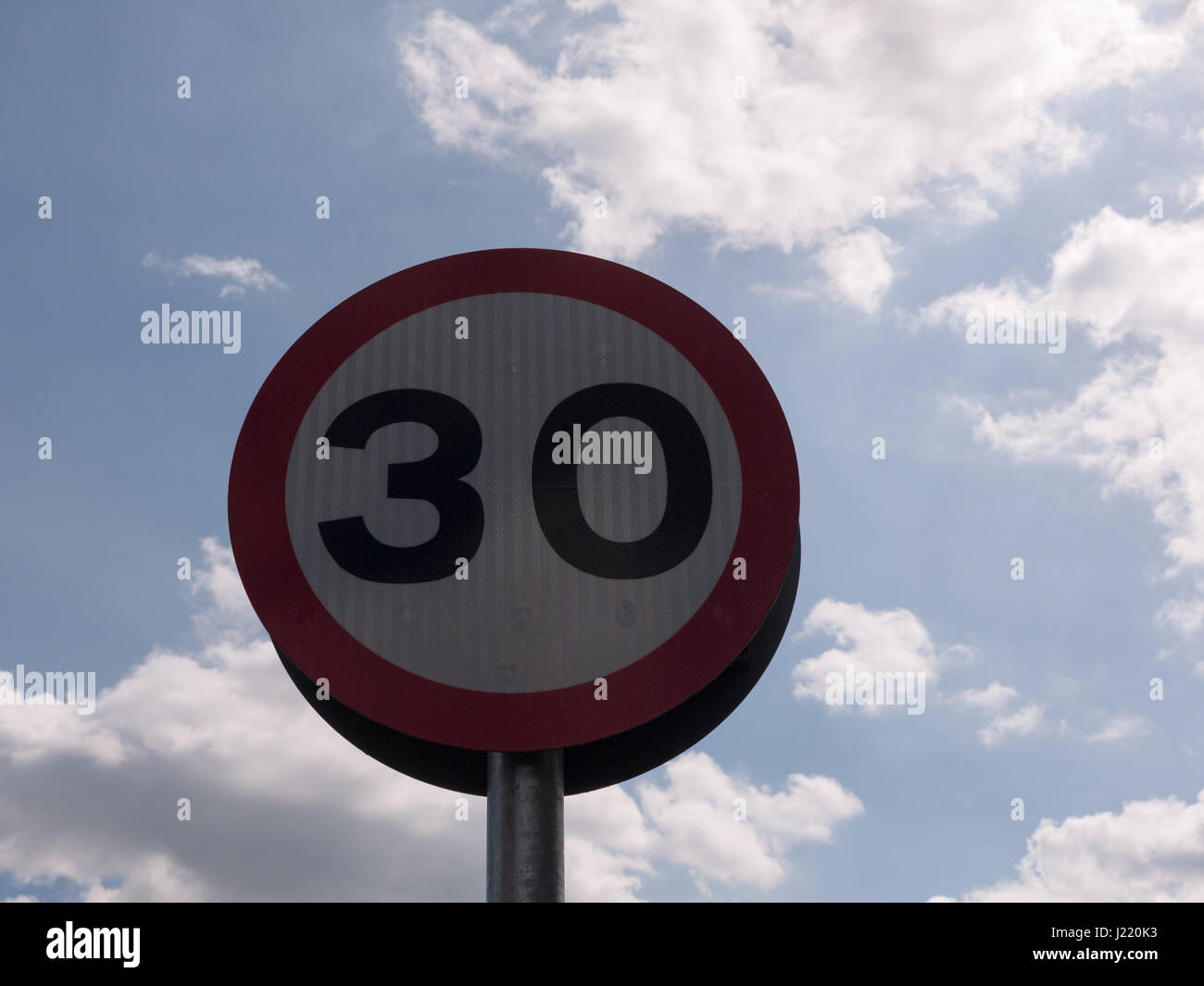 a road traffic sign with a sky background saying 30 speed limit near ...