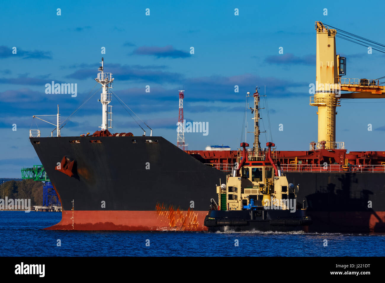 Black cargo ship mooring at the port with tug ship support Stock Photo ...