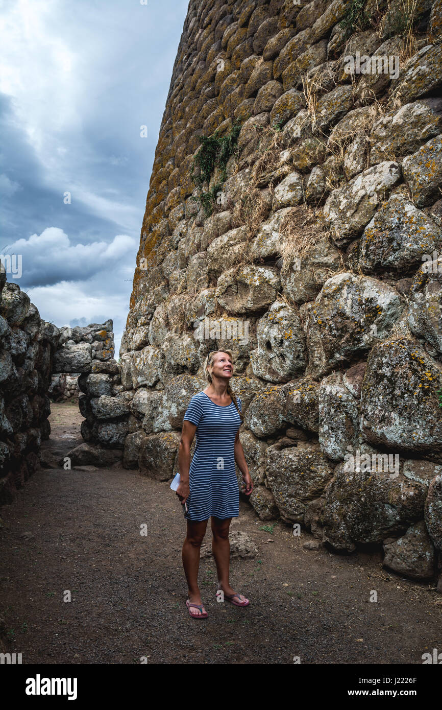 Girl wandering in the walls of nuraghe site with picturesque sky in the ...