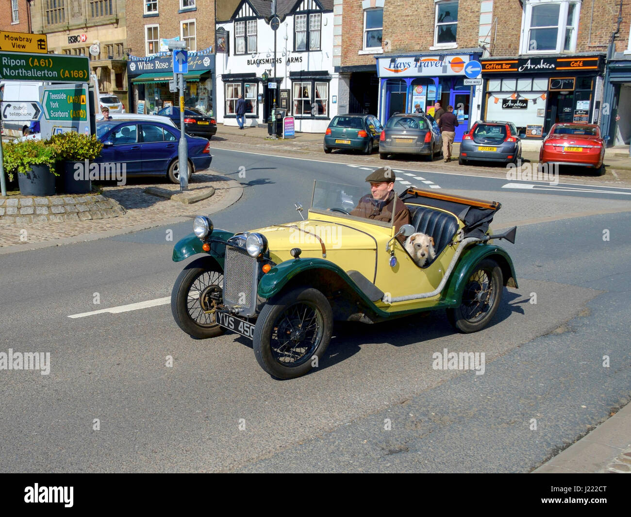 A man driving an early Austin Seven open top car with a dog in the ...