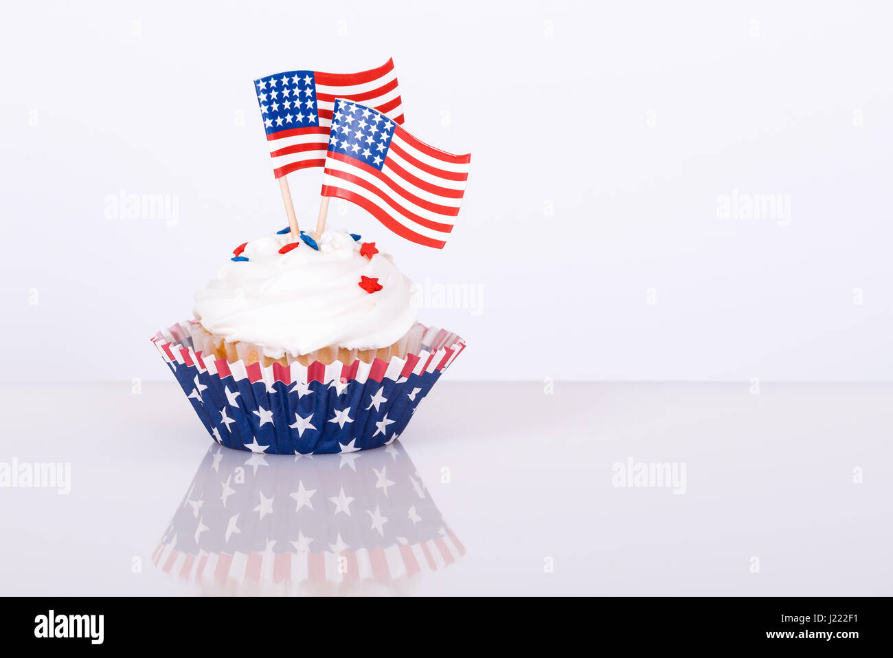 Patriotic 4th of July cupcake with decorative American flags agains ...