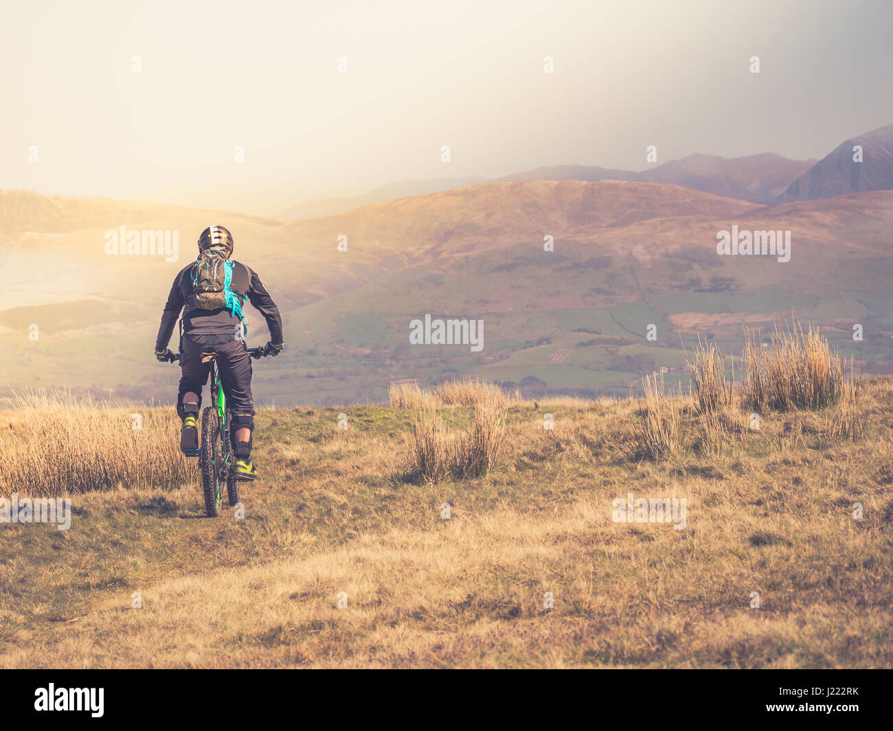 A mountain biker rides along top of Dent fell in the Lake district ...
