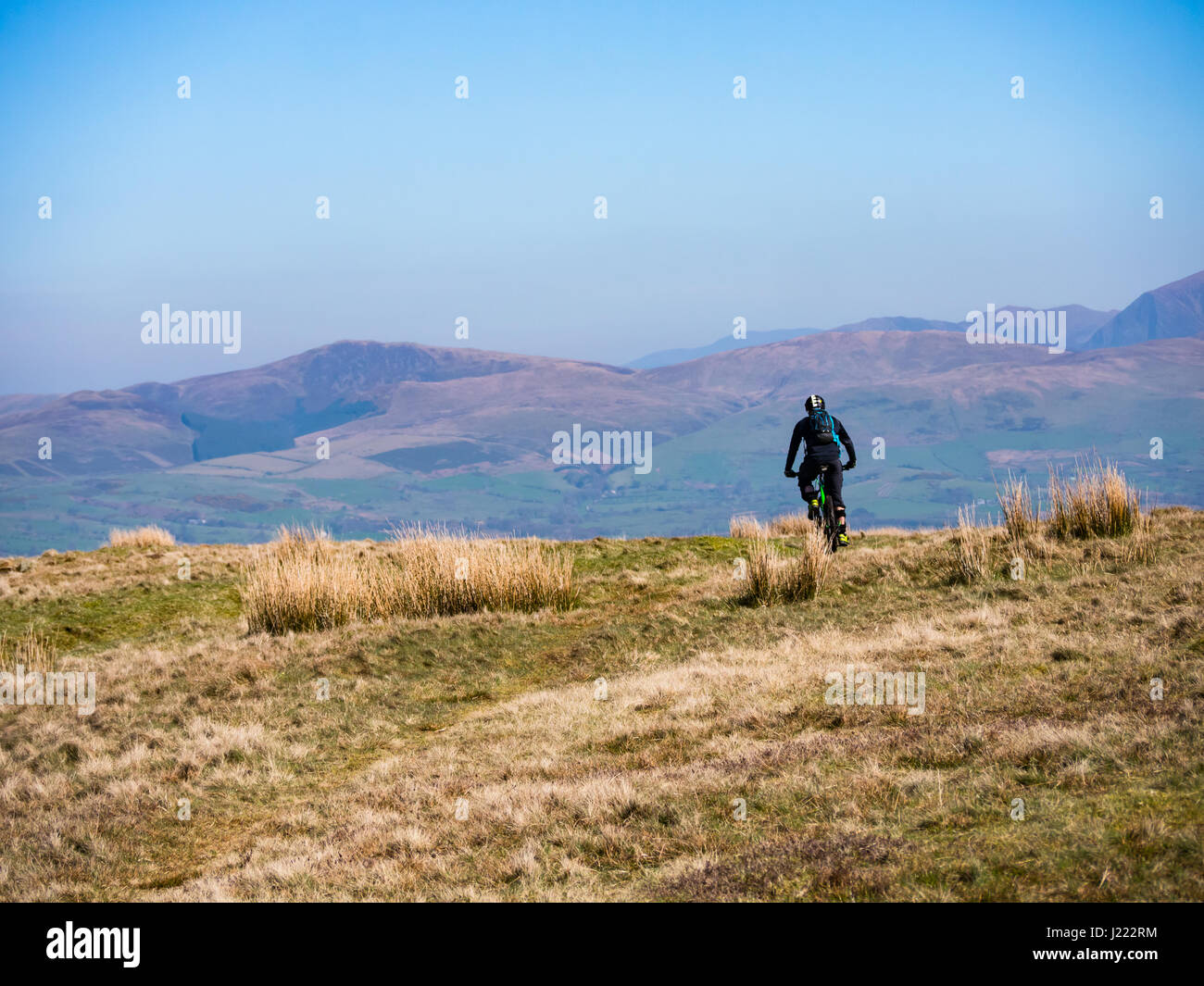 A mountain biker rides along top of Dent fell in the Lake district ...