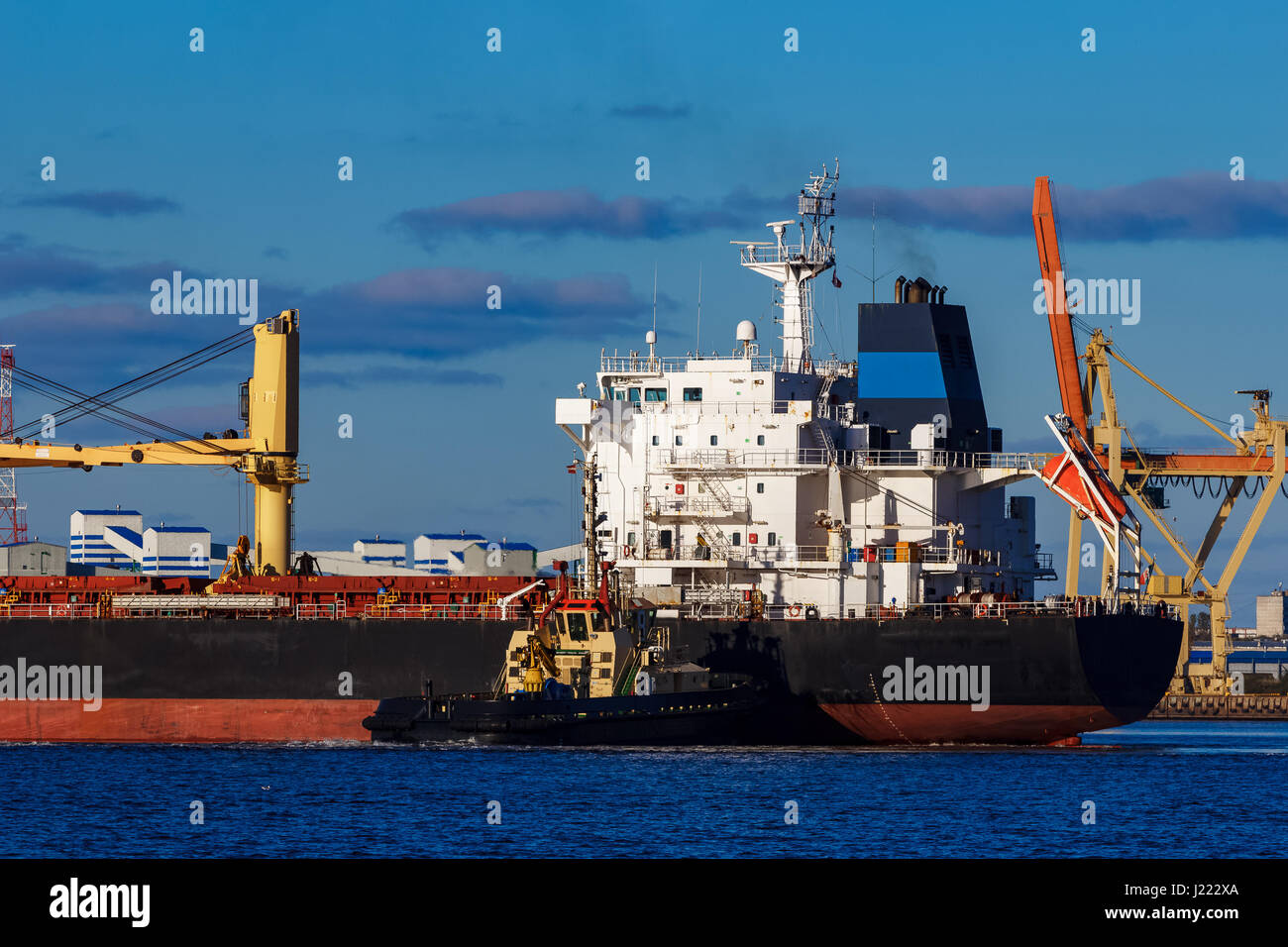 Black cargo ship mooring at the port with tug ship support Stock Photo ...