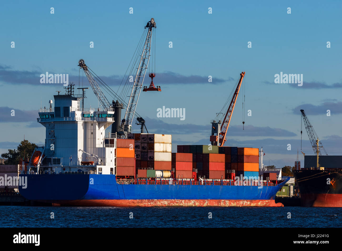 Blue container ship loading in cargo port of Europe Stock Photo - Alamy
