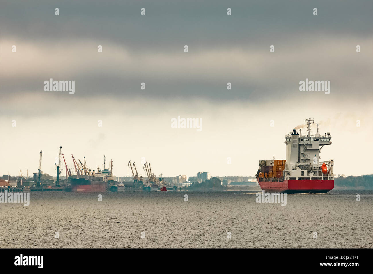 Red cargo container ship entering the port of Riga in cloudy day Stock ...
