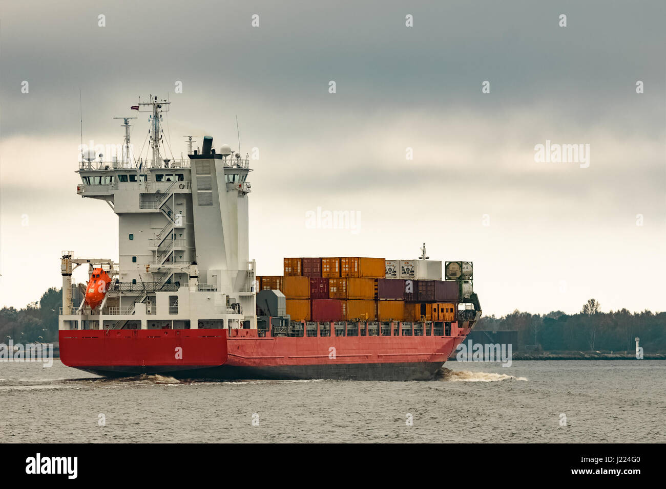 Red cargo container ship entering the port of Riga in cloudy day Stock ...