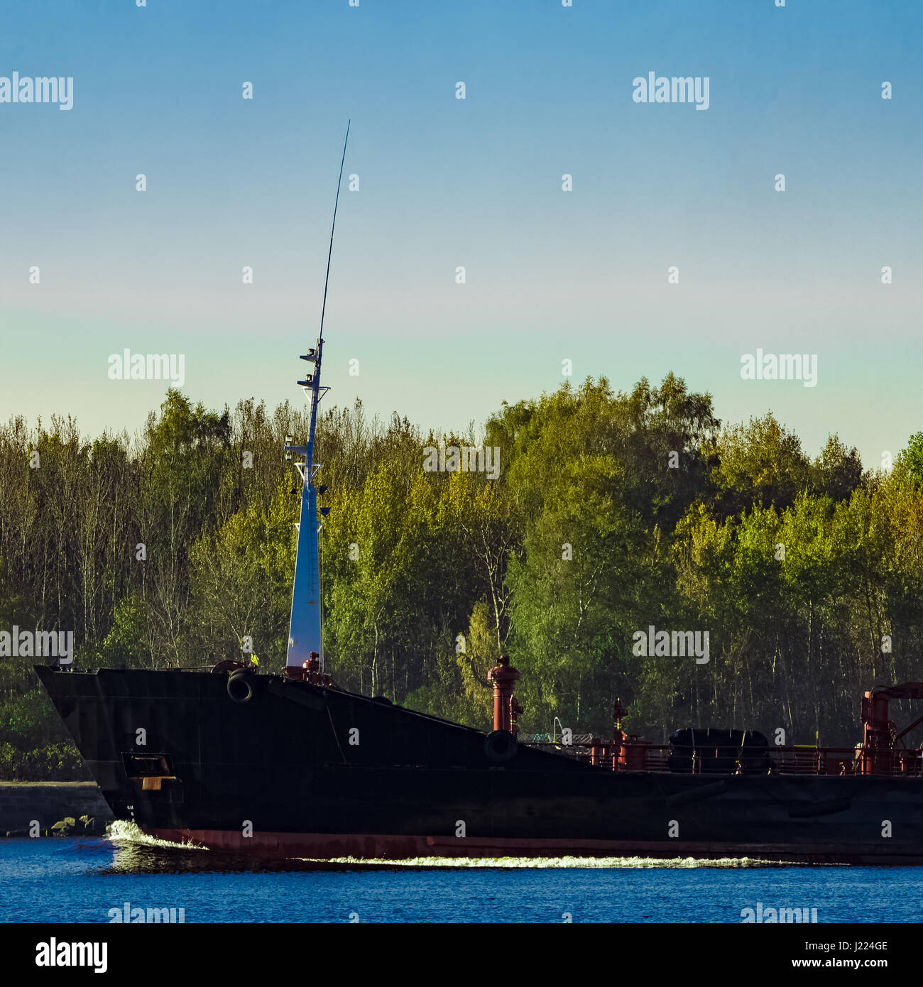 Black cargo oil tanker's bow against summer green trees Stock Photo - Alamy