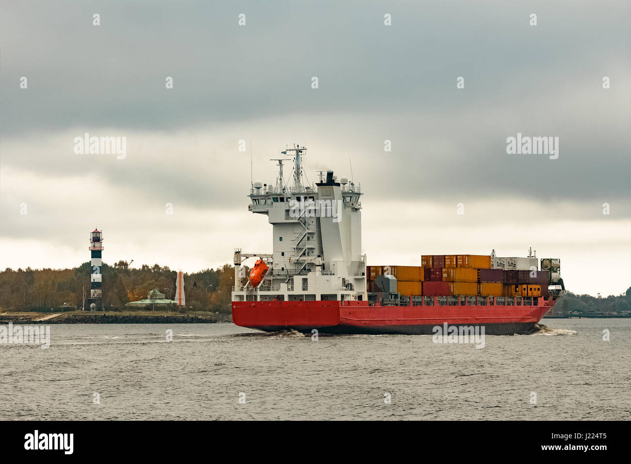 Red cargo container ship entering the port of Riga in cloudy day Stock ...