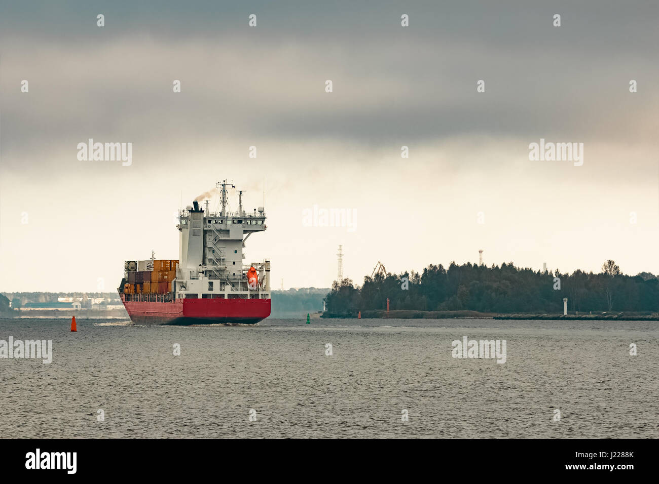 Red cargo container ship entering the port of Riga in cloudy day Stock ...