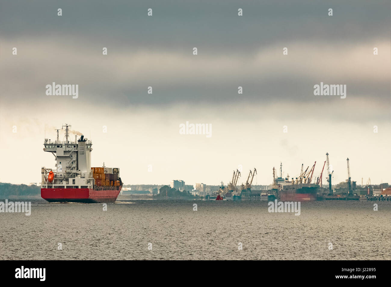 Red cargo container ship entering the port of Riga in cloudy day Stock ...