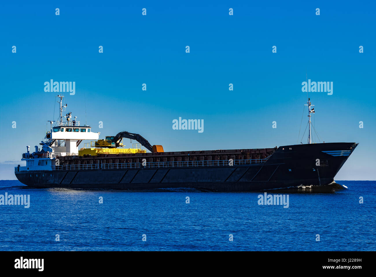 Black cargo ship with long reach excavator moving by baltic sea Stock ...