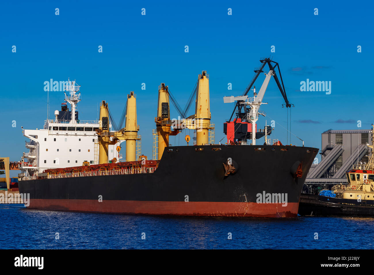 Black cargo ship mooring at the port with tug ship support Stock Photo ...