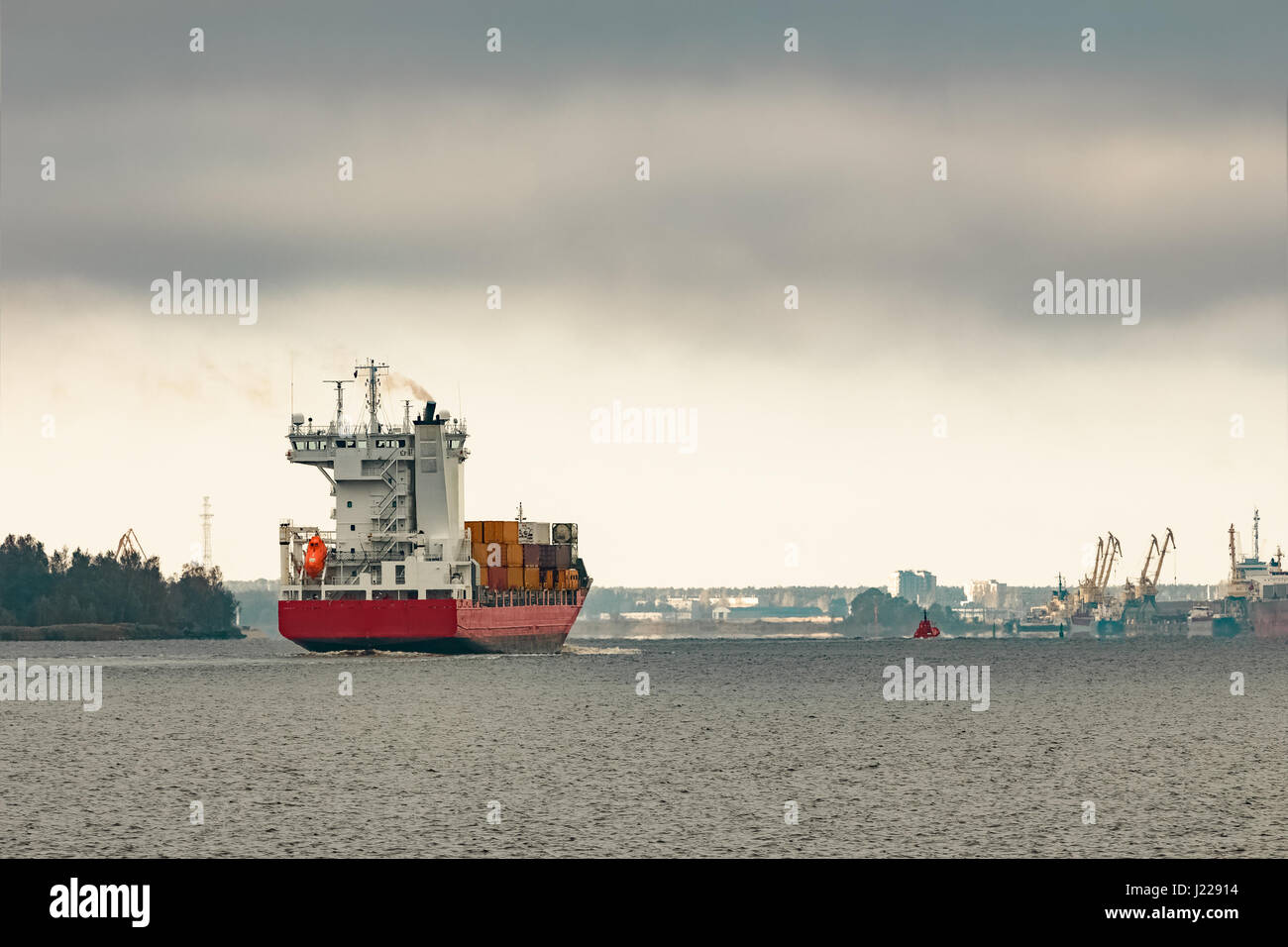 Red cargo container ship entering the port of Riga in cloudy day Stock ...