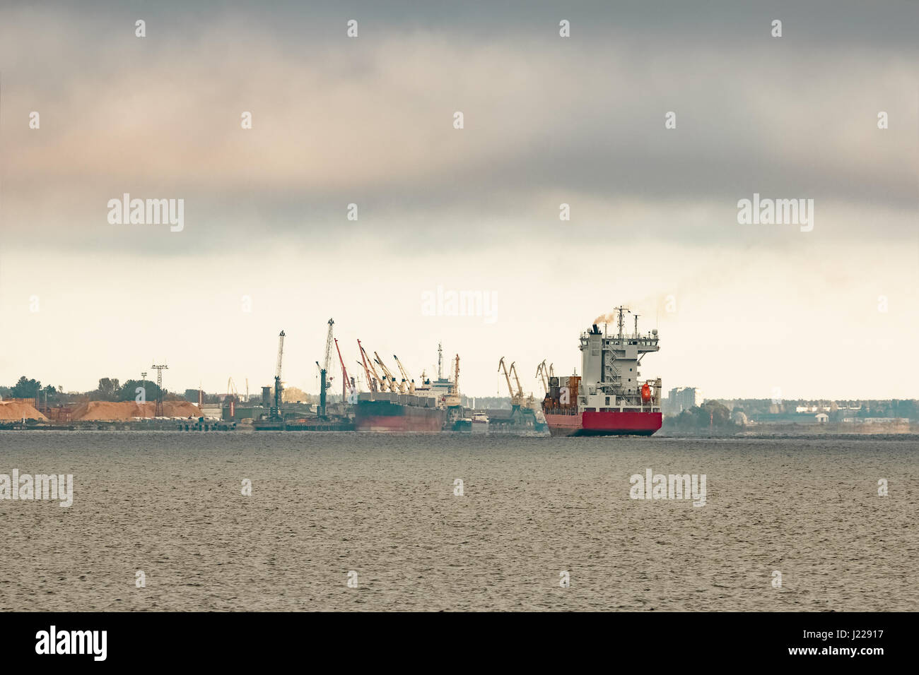 Red cargo container ship entering the port of Riga in cloudy day Stock ...