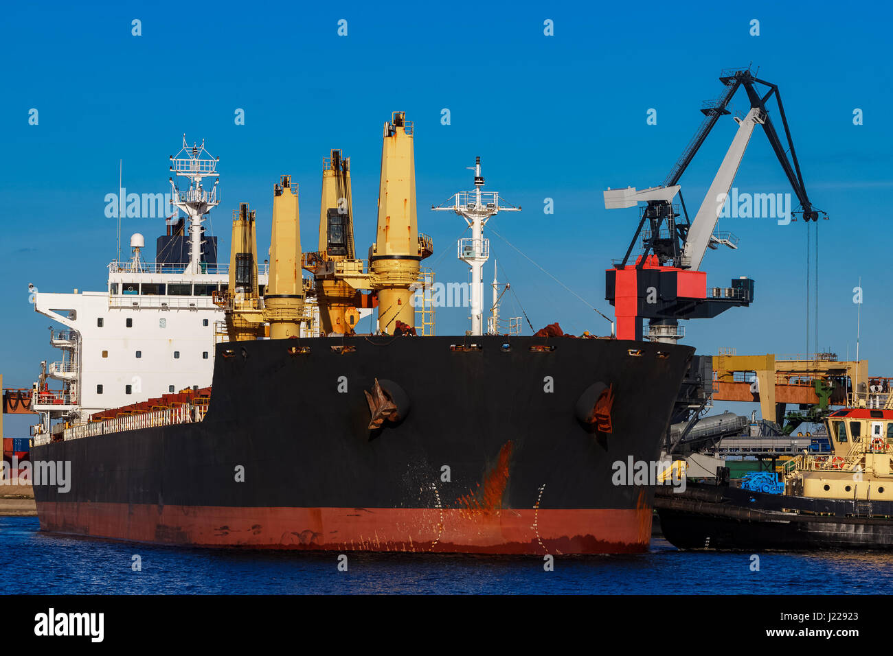 Black cargo ship mooring at the port with tug ship support Stock Photo ...